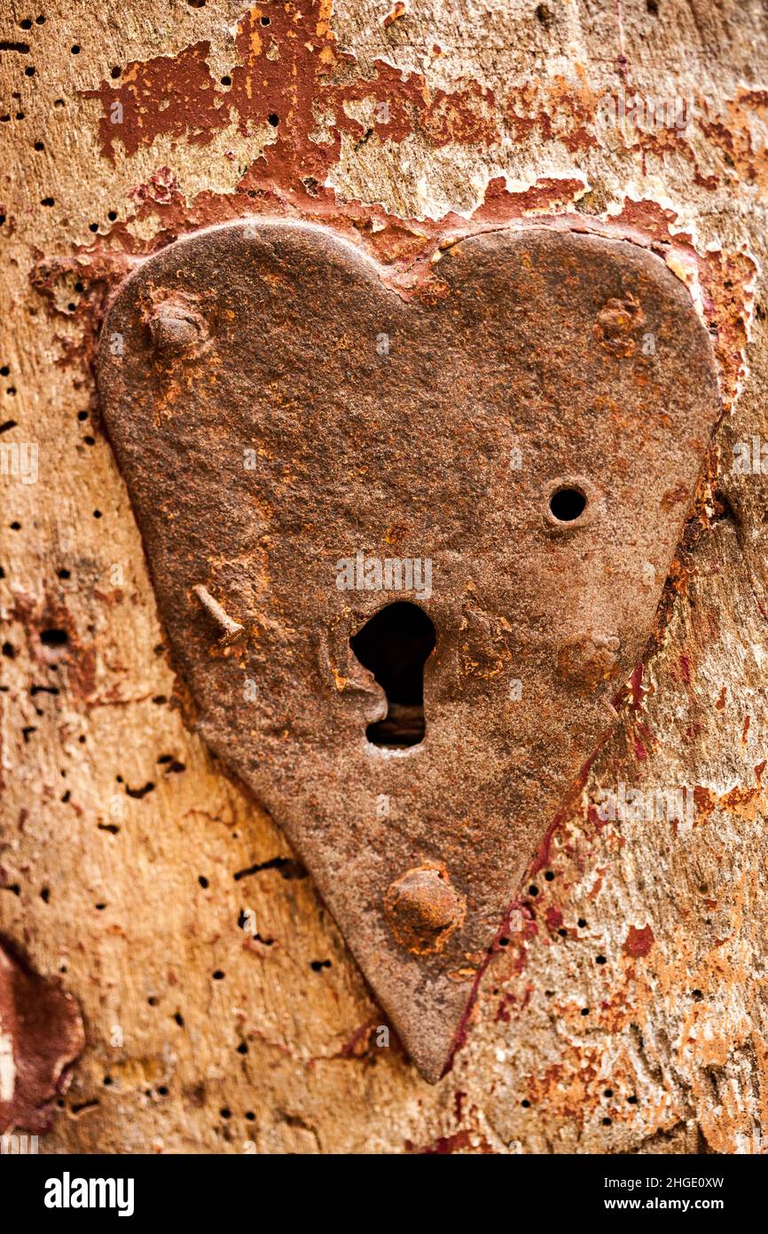 Antique heart shaped metal key hole on an old red painted rustic door ...
