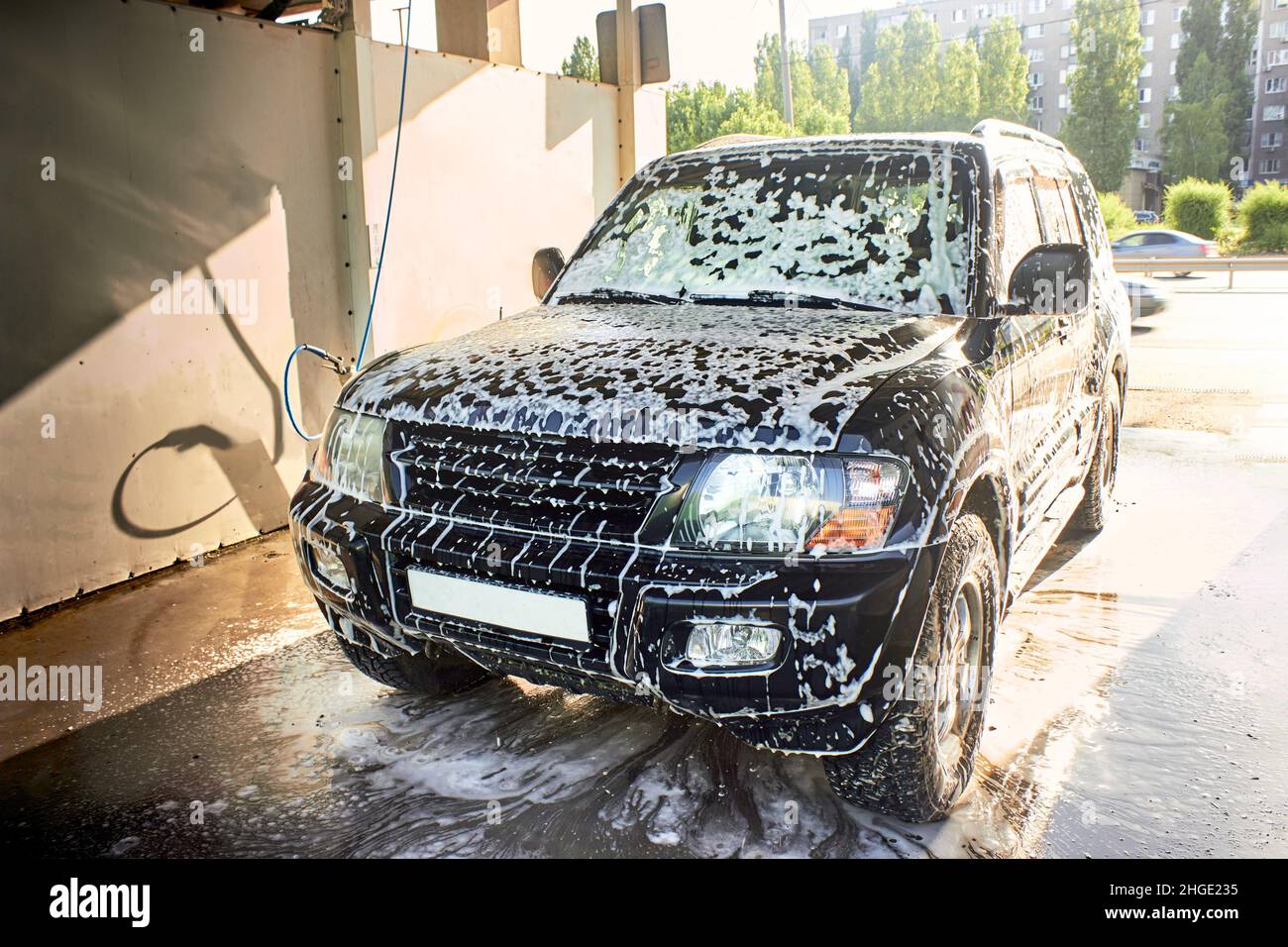 A black SUV car at a self-service car wash. Washing the car with your ...
