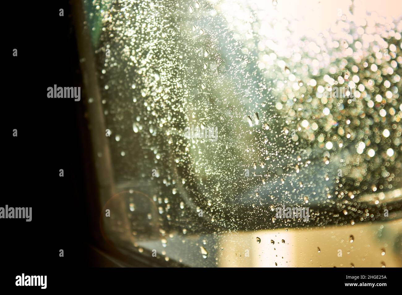 Water drops on the car window. The sunset sunlight shines on the glass ...