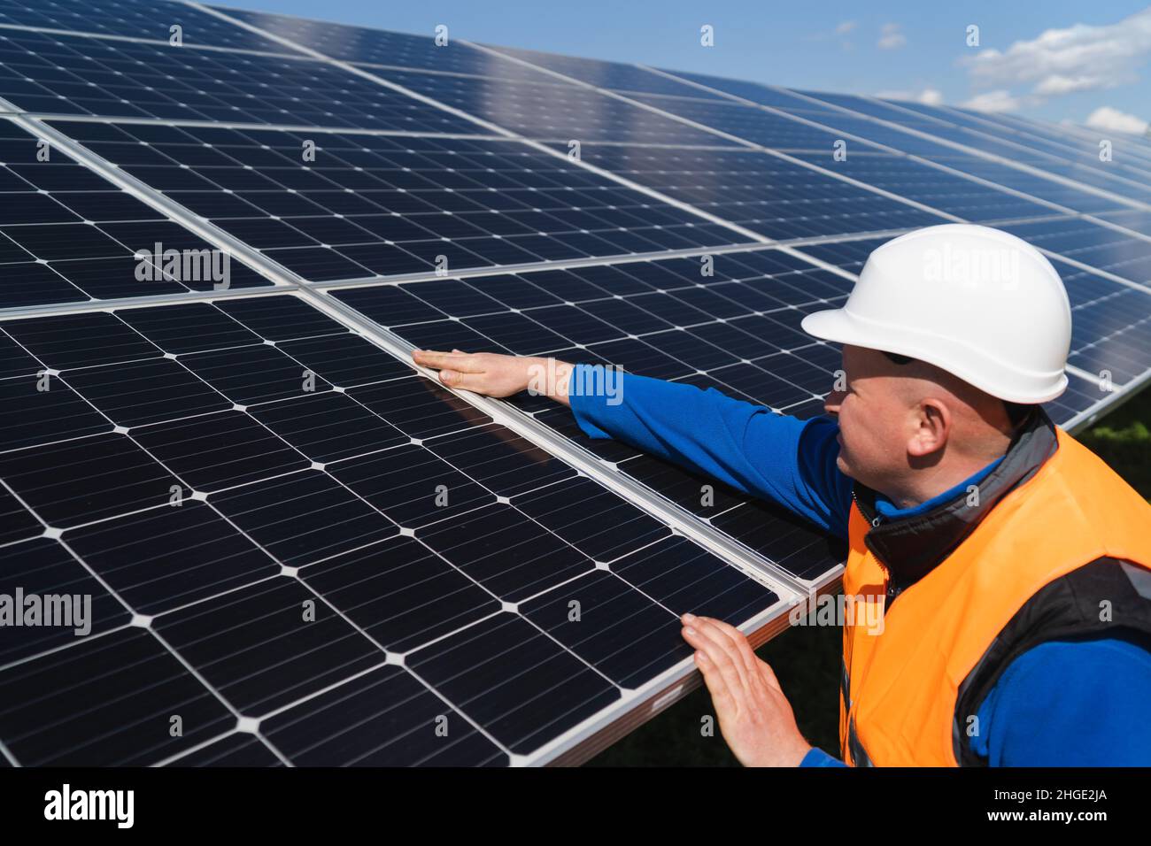 Solar power plant worker in hard hat checks the surface of the ...