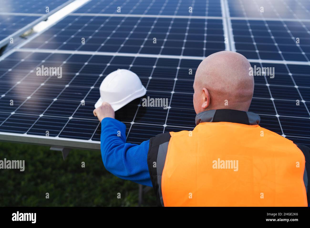 Male worker of a solar power plant takes a helmet that lies on the ...