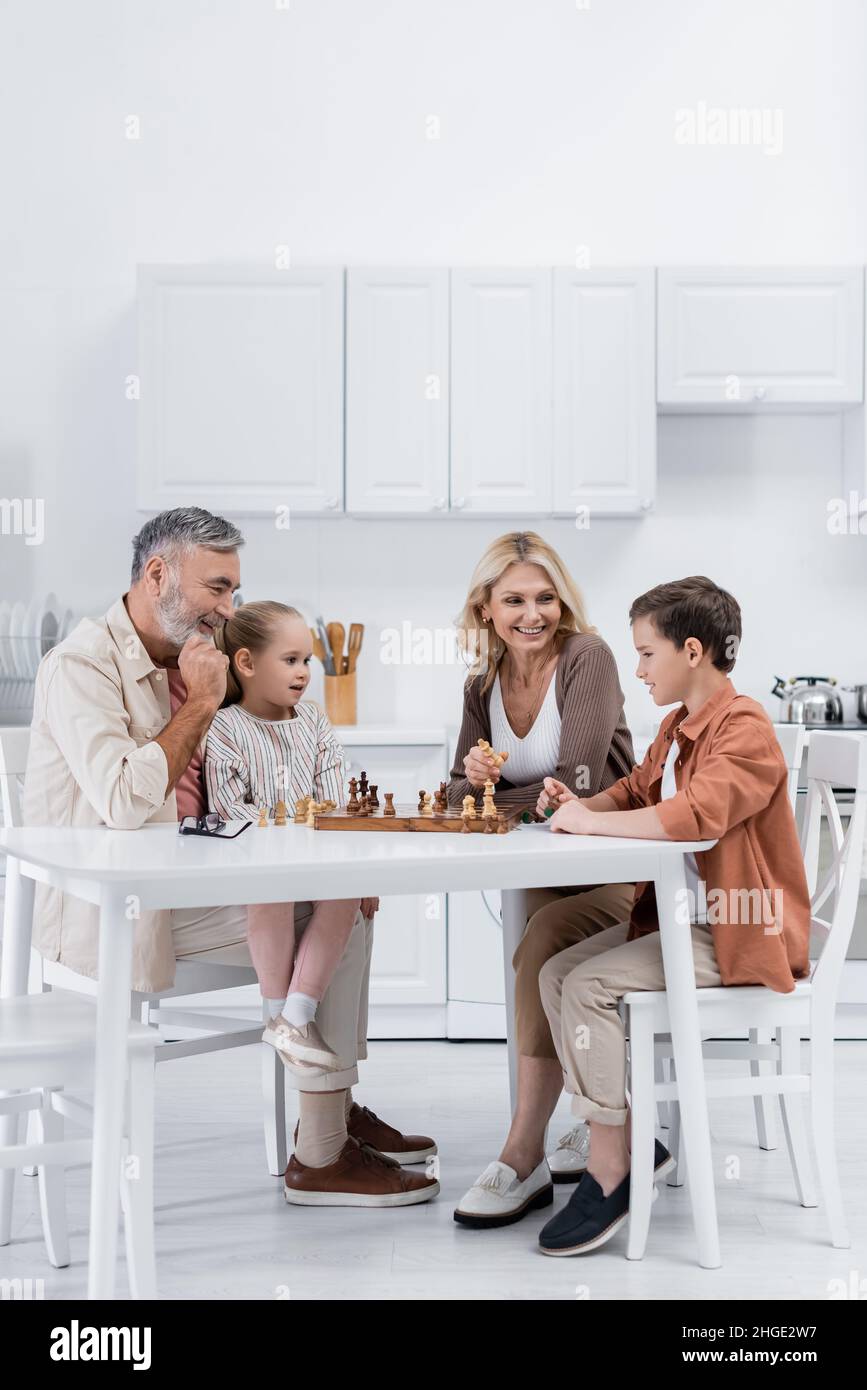 happy grandparents playing chess with kids in kitchen Stock Photo - Alamy