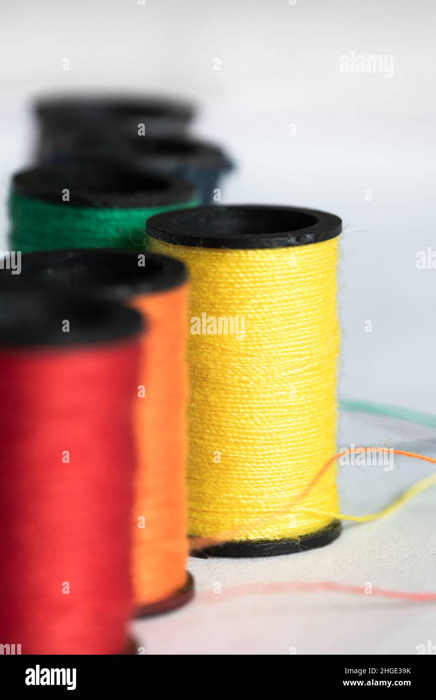 Spool of yellow tread with red and orange thread in foreground and ...