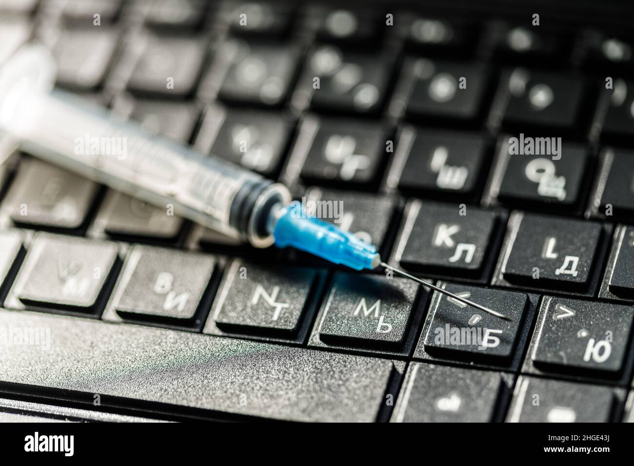a disposable syringe lies on the laptop keyboard. online drug ...