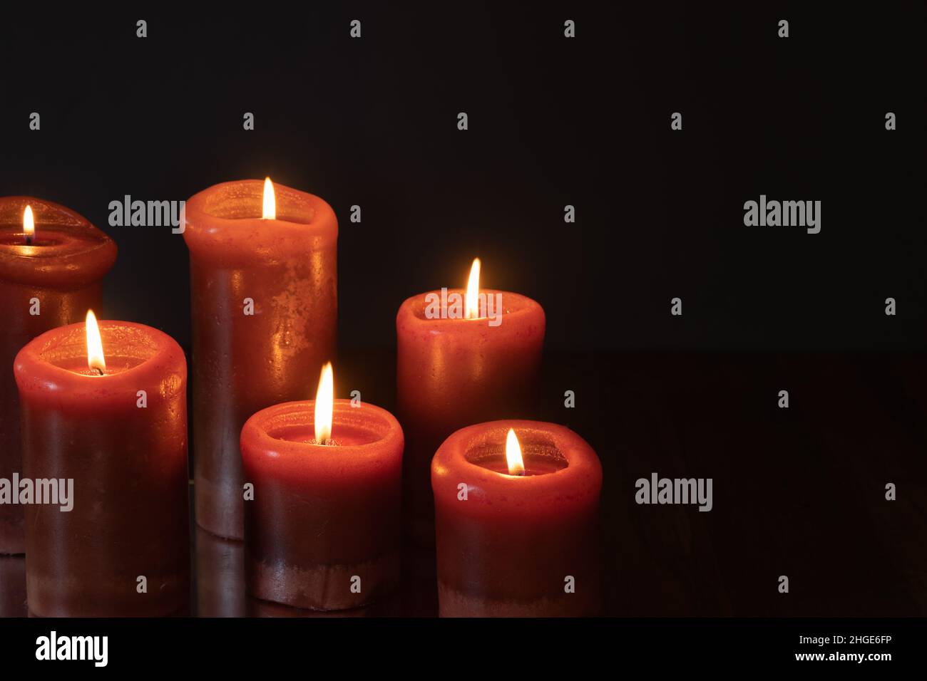 Red candles lit in a dark room with a black background with copy space ...