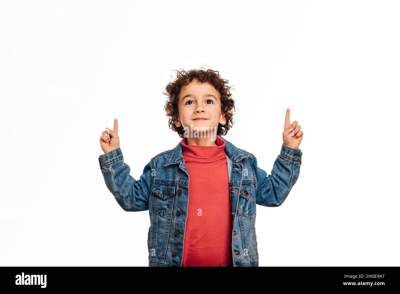 Young boy pointing up to show something while standing on an isolated ...