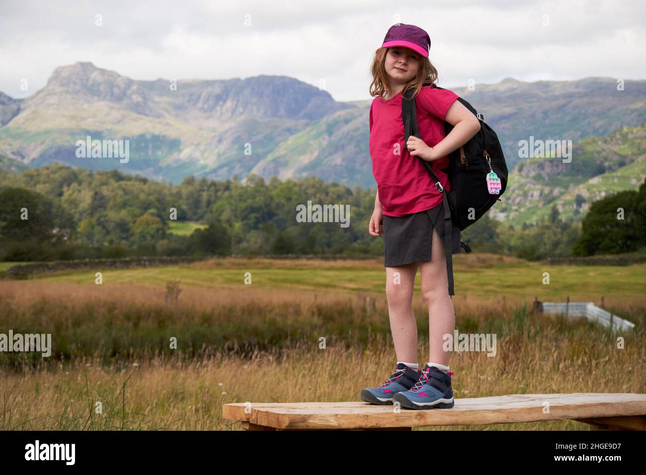 young seven year old girl in hiking clothing standing on platform in ...