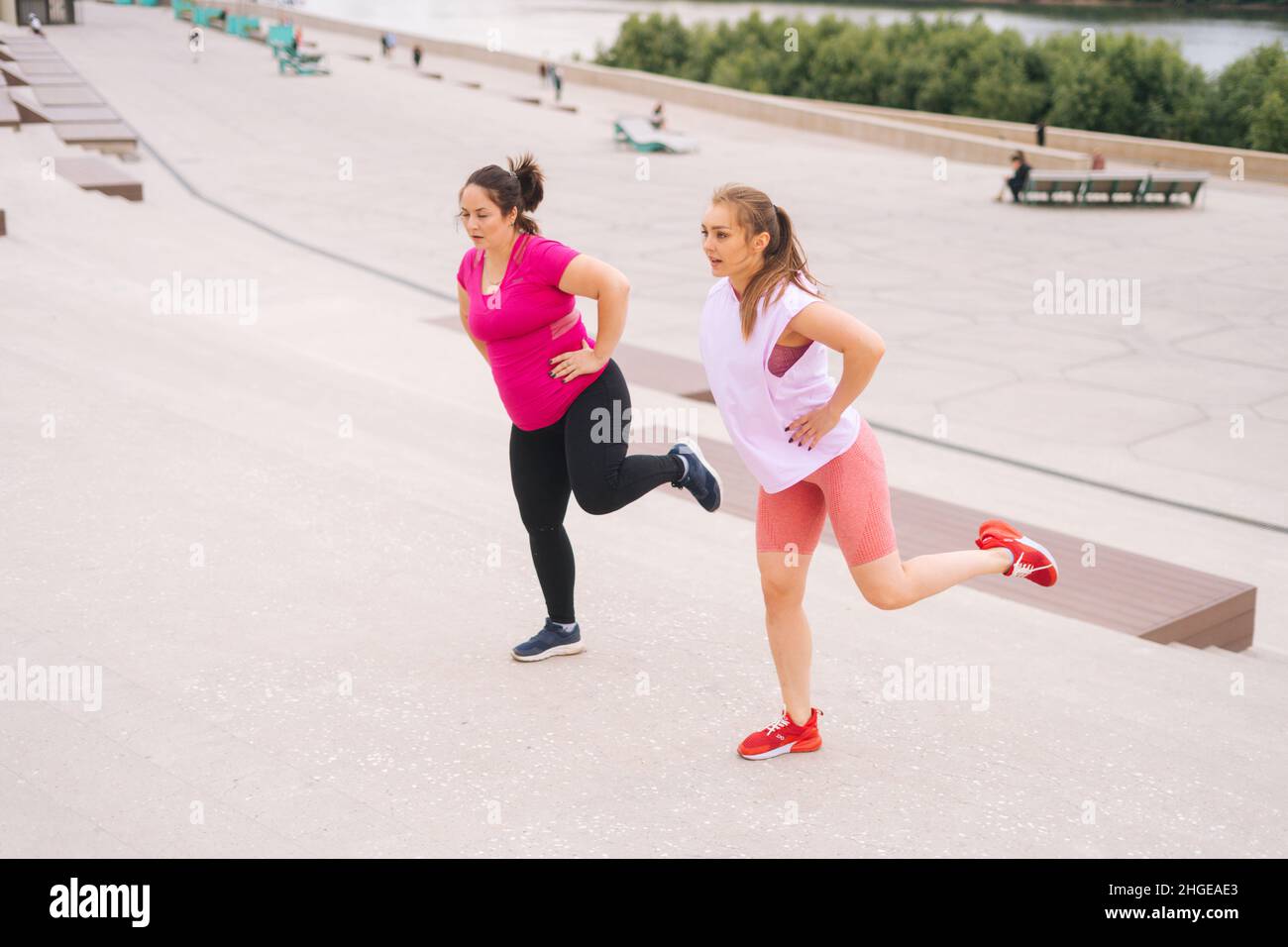 Personal fitness female trainer helping fat woman lose weight outside ...