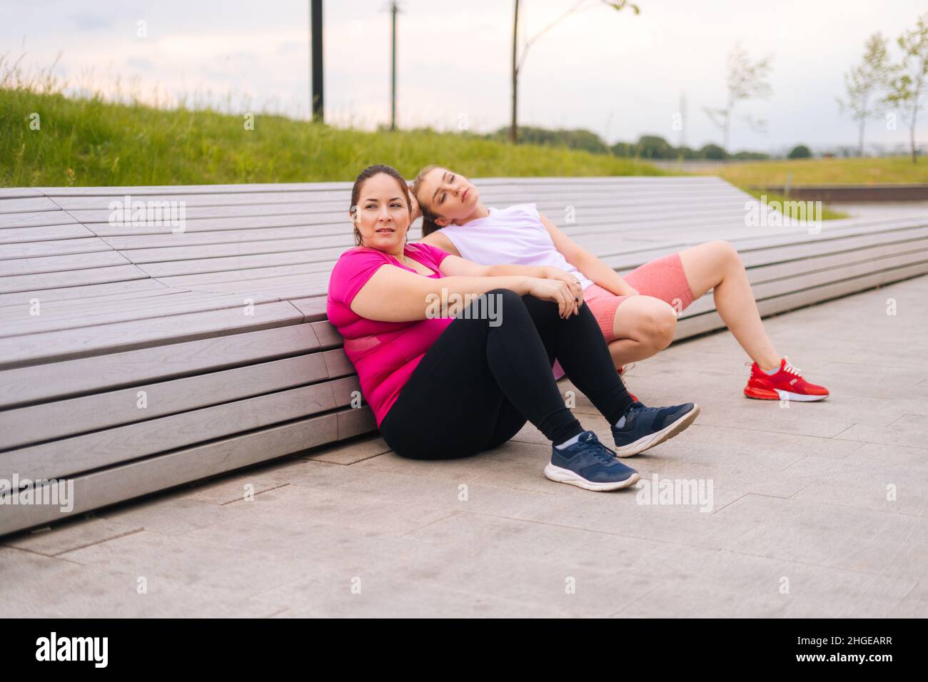 Wide shot of tired obese young woman resting by bench after intense ...