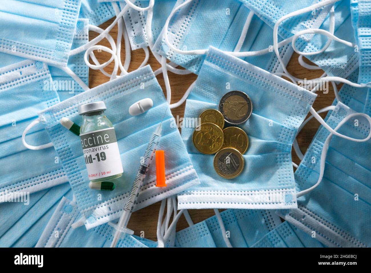 Close up photo of medical masks with coins and vial of coronavirus ...