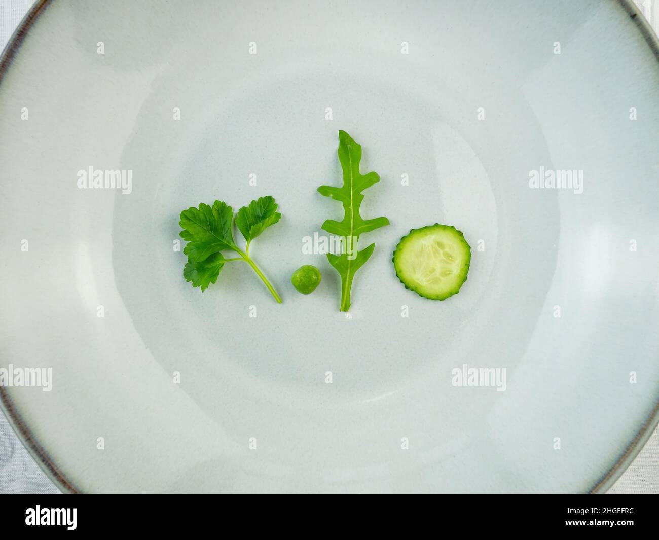 Plate with one pea, lettuce, cucumber slice and parsley Stock Photo - Alamy