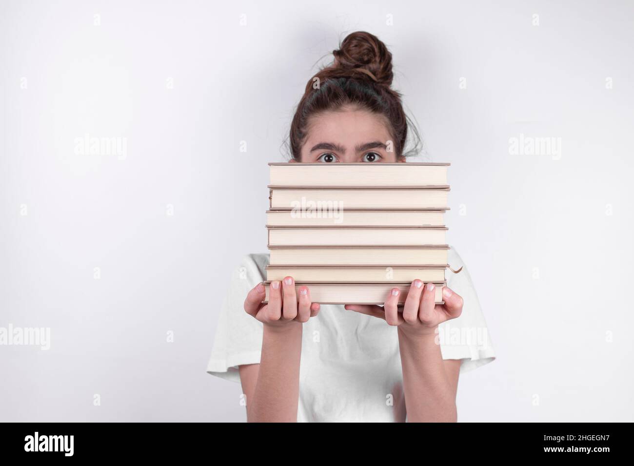 Girl covers half his face with books and showing only his eyes on white ...