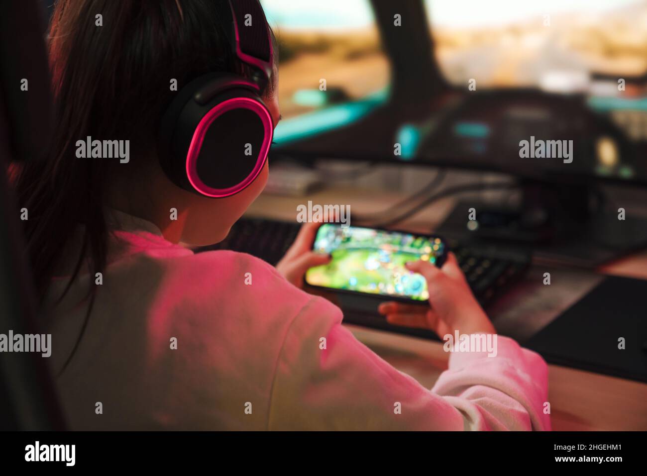 Back view of a young woman gamer playing video games on smartphone and ...