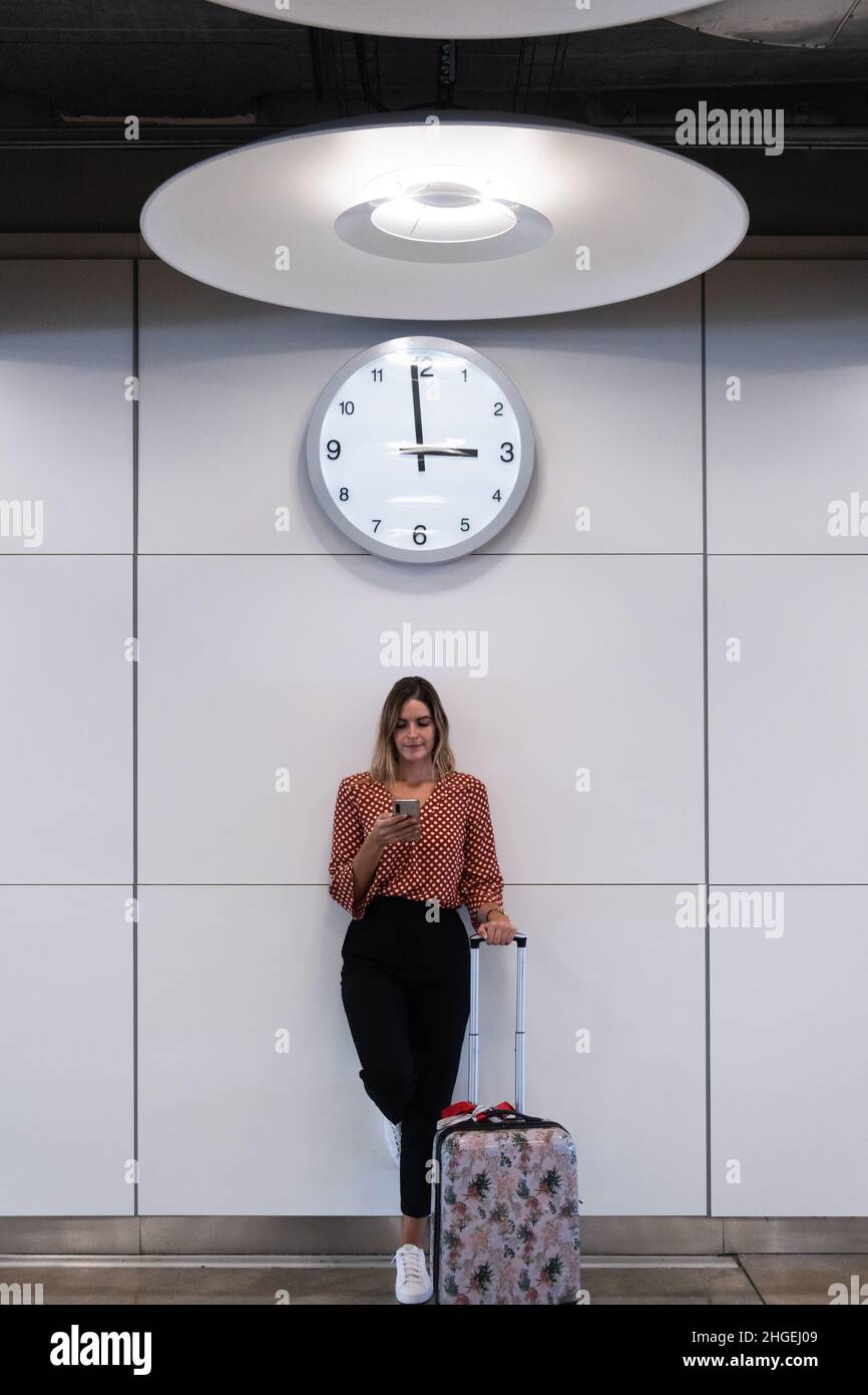 woman reading the smartphone under the clock with symmetry Stock Photo ...