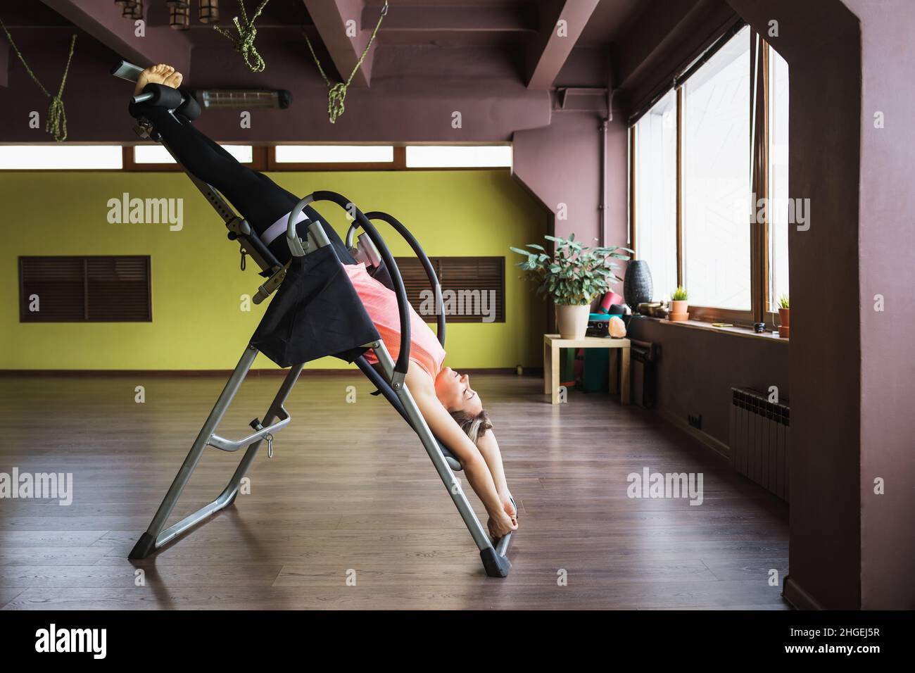A woman doing inversion therapy hanging upside down on an inversion ...