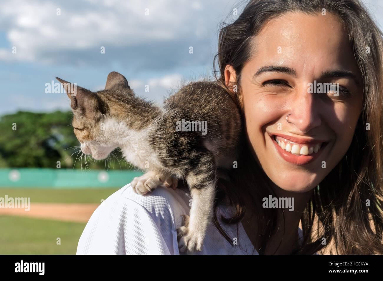 Closeup photo of a smiling young girl with a small cat on her shoulder ...