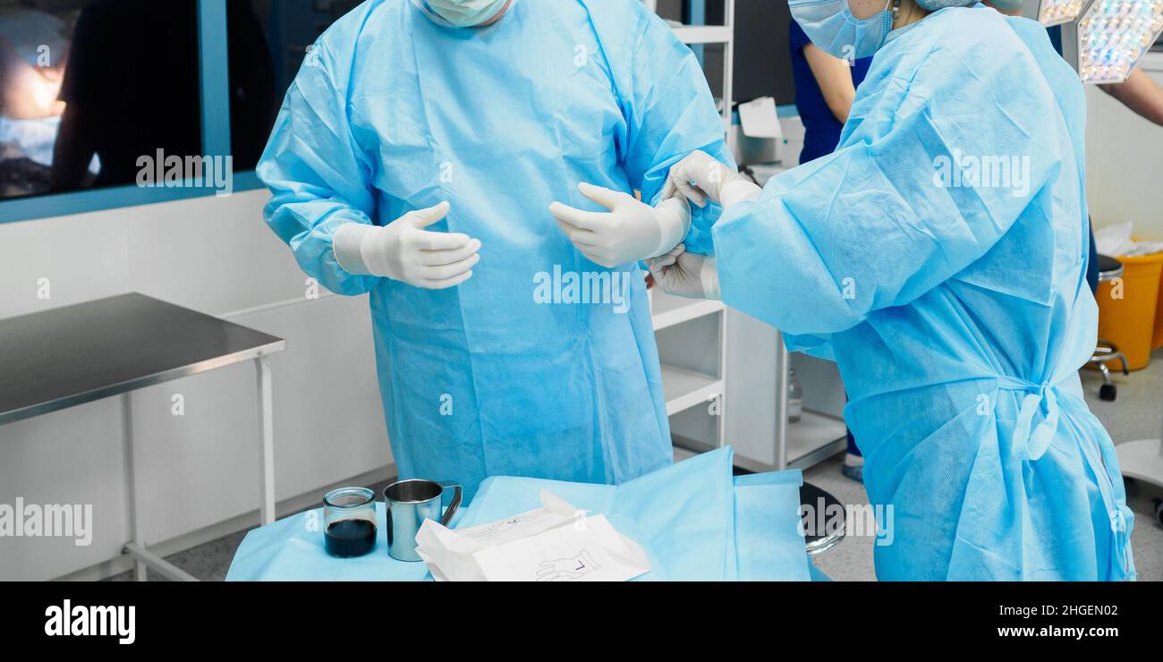 Surgeons in blue uniforms wear sterile gloves before surgery Stock ...