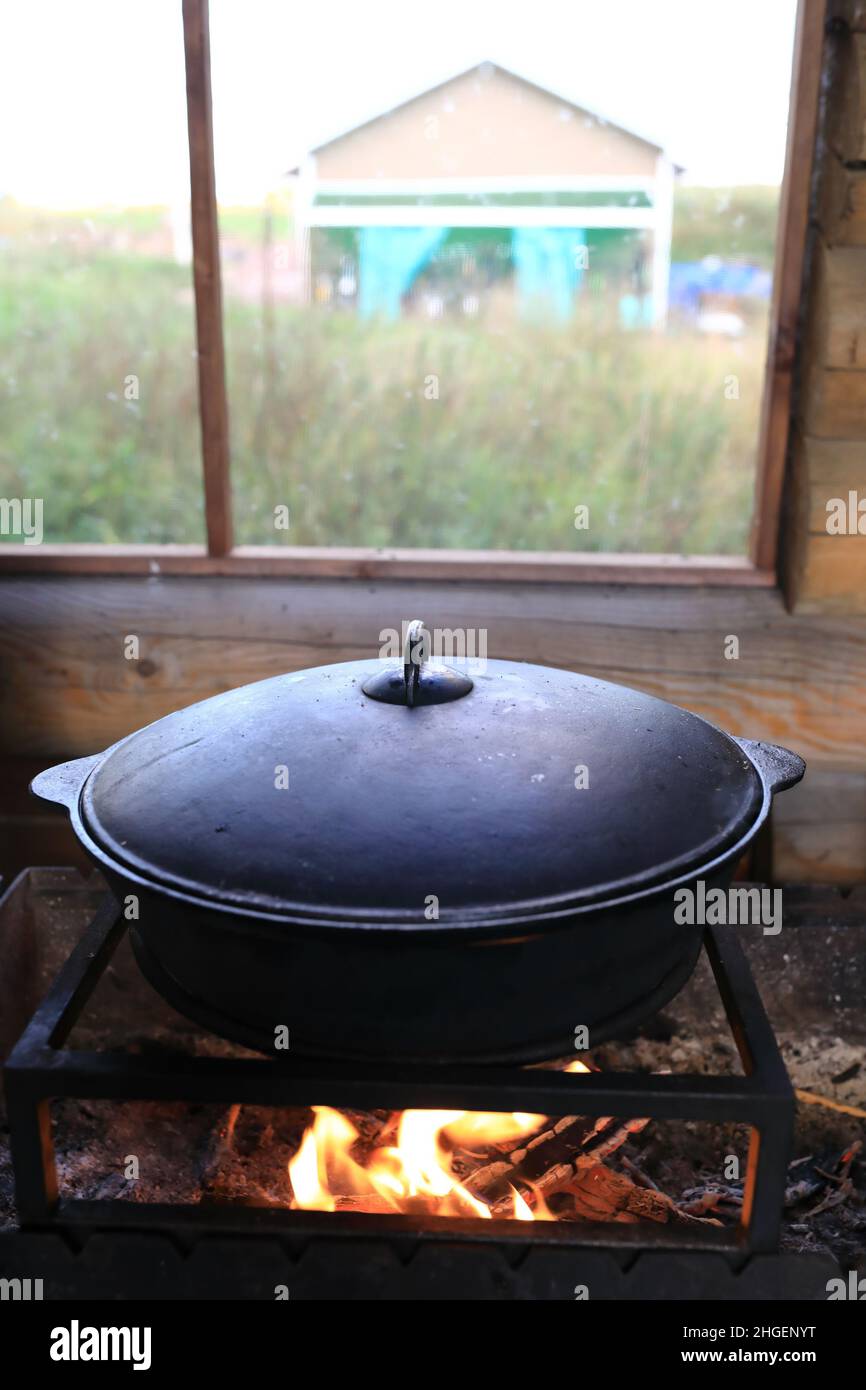 Cooking food in cauldron on fire in gazebo Stock Photo - Alamy