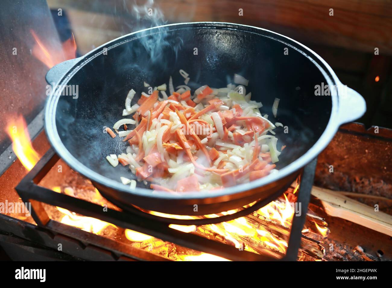 Frying carrots with onions in cauldron on fire Stock Photo - Alamy
