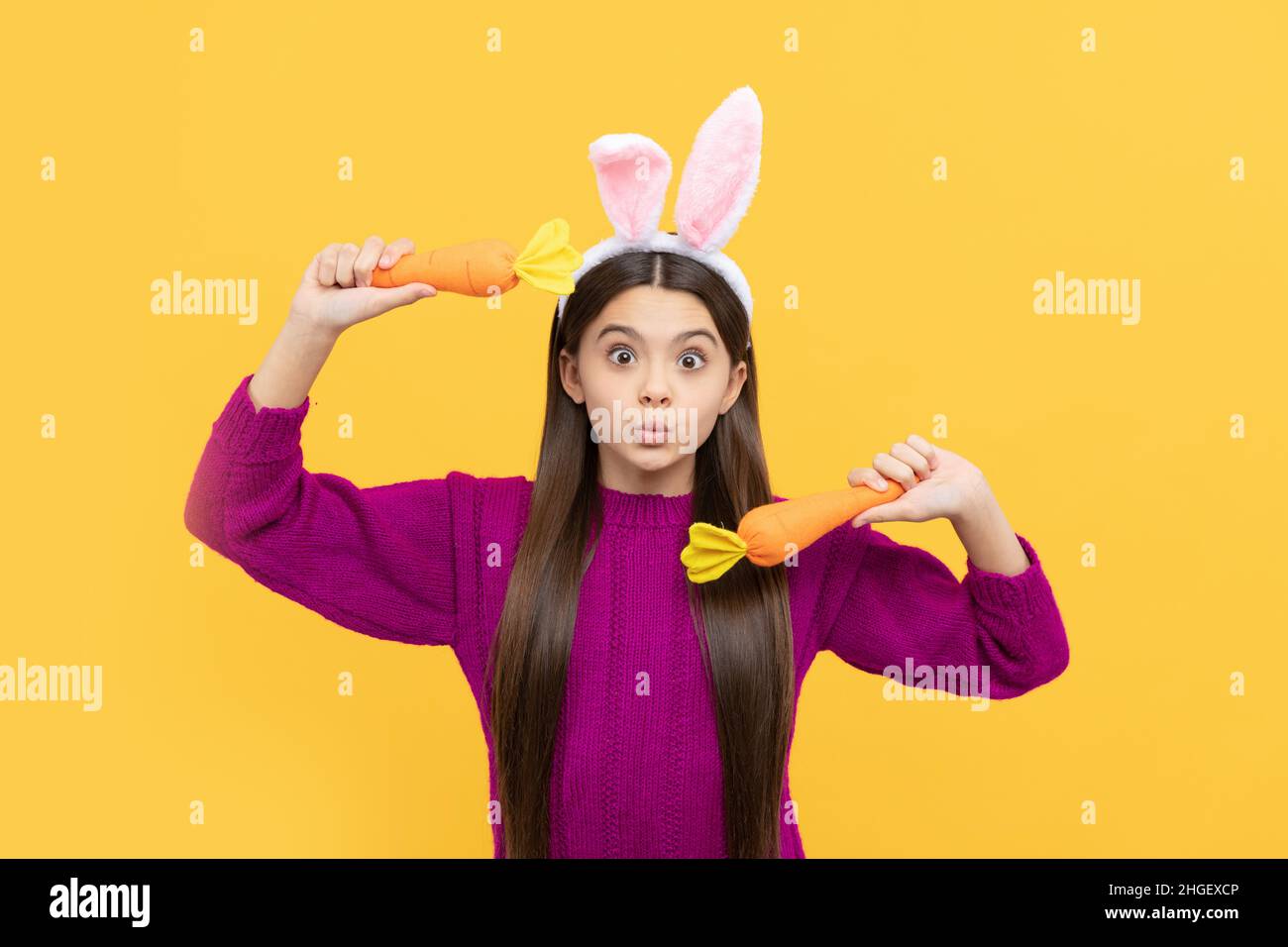 making faces. funny child in hare ears hold carrot. teenager girl wear ...