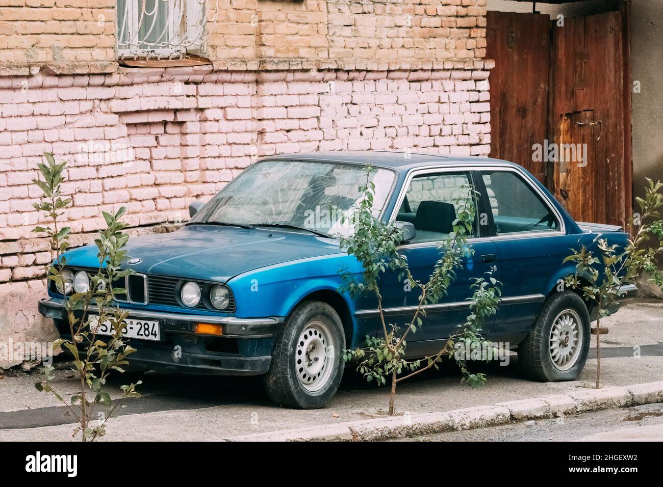 Old rusty sedan car BMW 3 Series (E30) parking on street. The BMW E30 ...