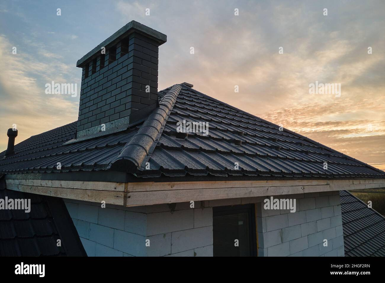 Chimney on house roof top covered with metallic shingles under ...
