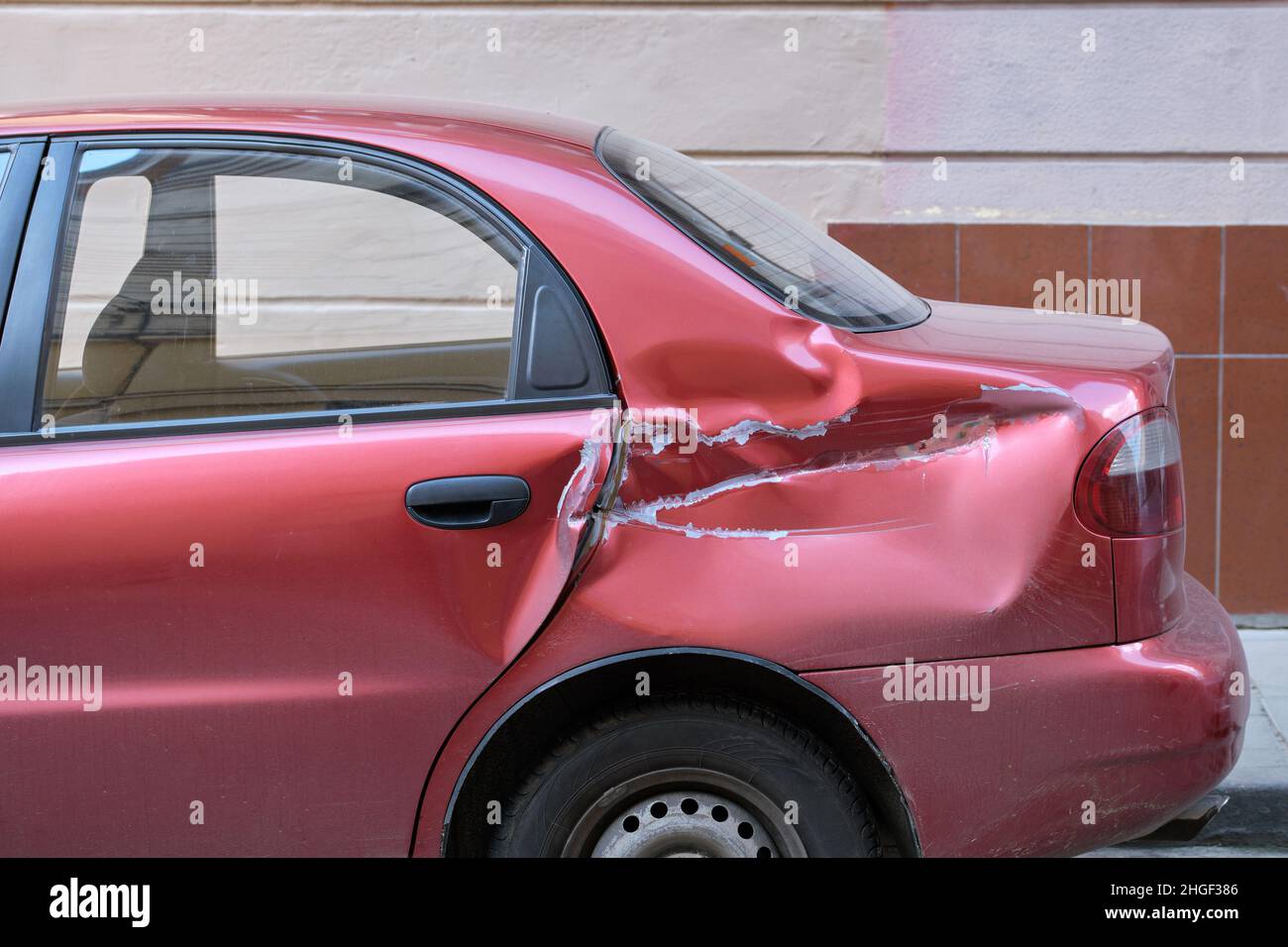 Dented car with damaged body parked on city street side. Road safety ...
