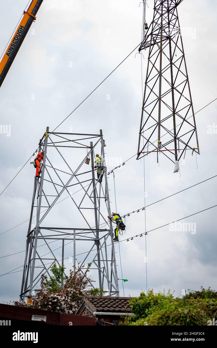 Workmen detach the upper half of an electric pylon which is lowered to ...
