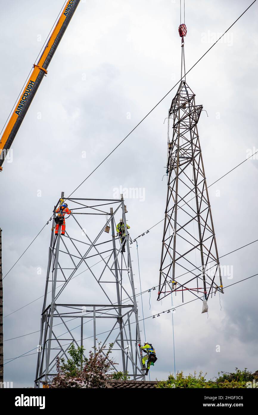 Workmen detach the upper half of an electric pylon which is lowered to ...