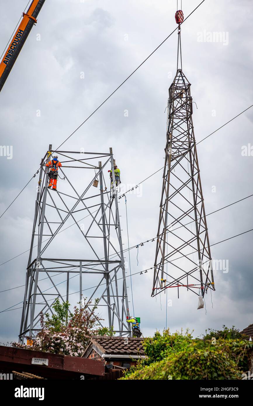Workmen detach the upper half of an electric pylon which is lowered to ...