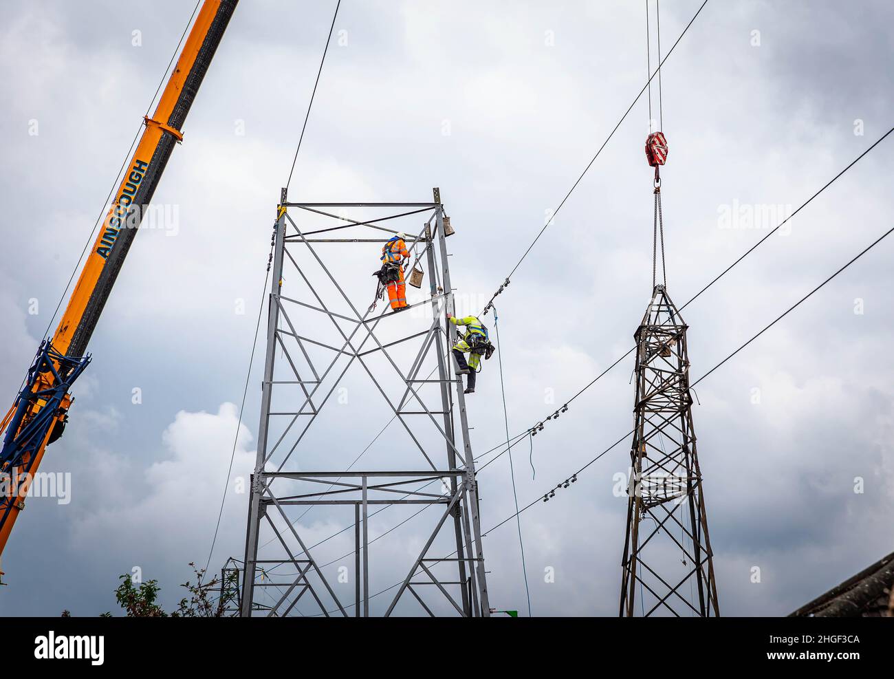 Workmen detach the upper half of an electric pylon which is lowered to ...
