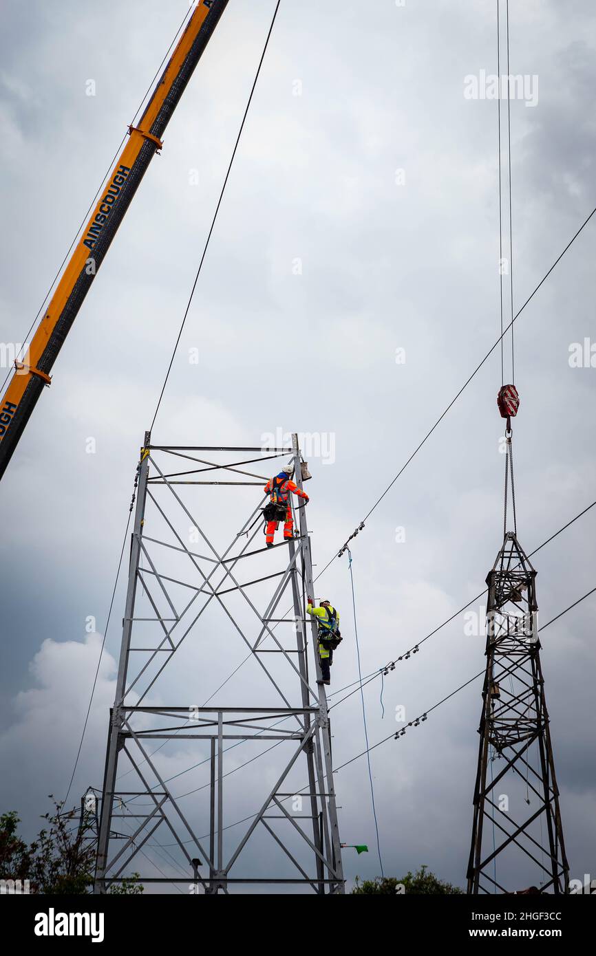 Workmen detach the upper half of an electric pylon which is lowered to ...