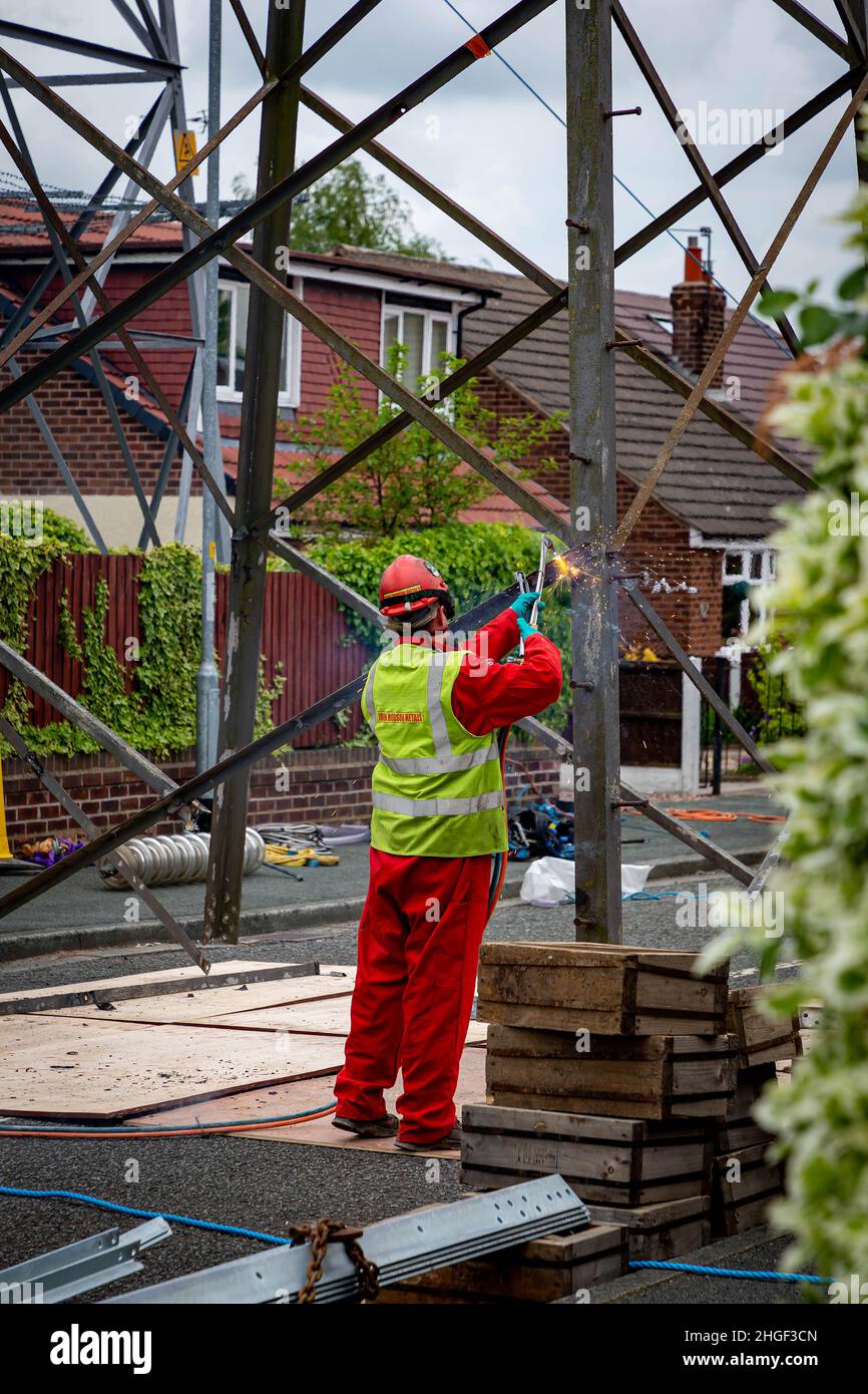 Workmen in PPE use oxy acetylene torches to cut out damaged parts of a ...