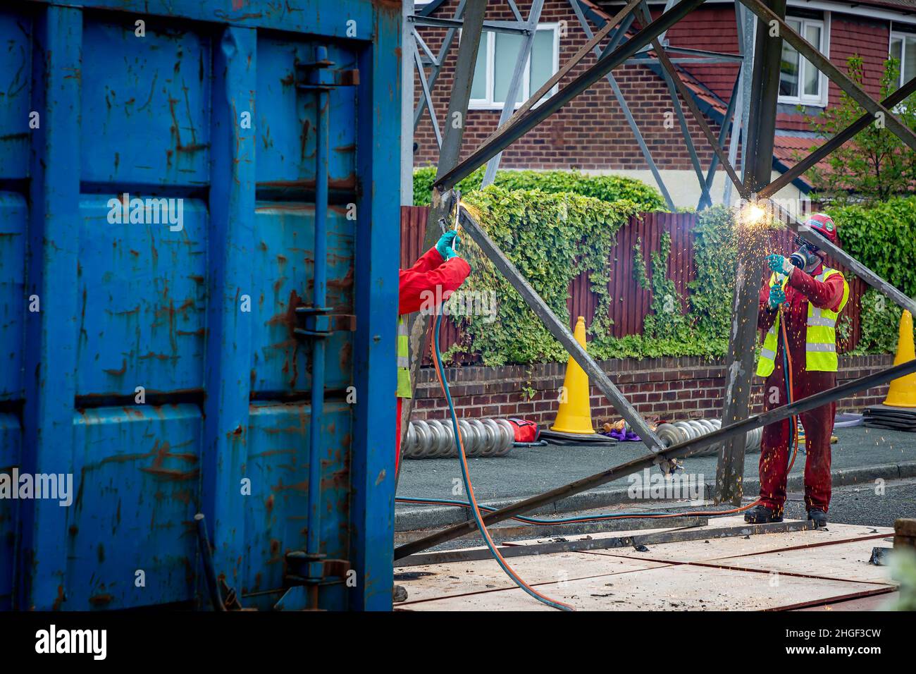 Workmen in PPE use oxy acetylene torches to cut out damaged parts of a ...