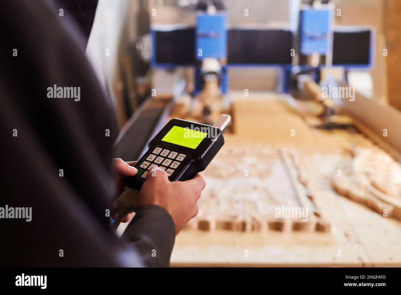 Hands close up holding the control panel of wood carving machine ...