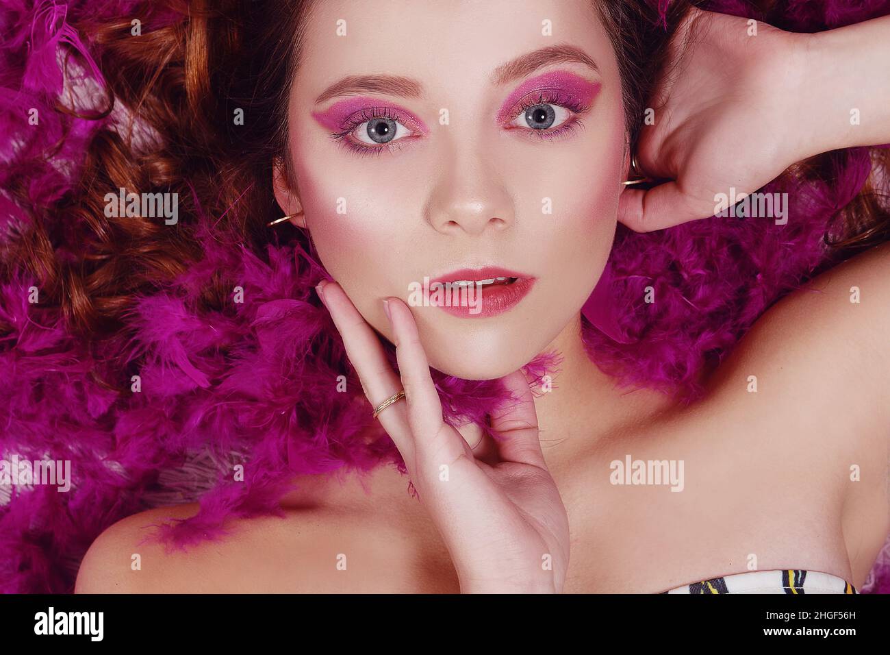 An Incredibly Beautiful Girl With Pink Fashion Makeup Lies In Feathers