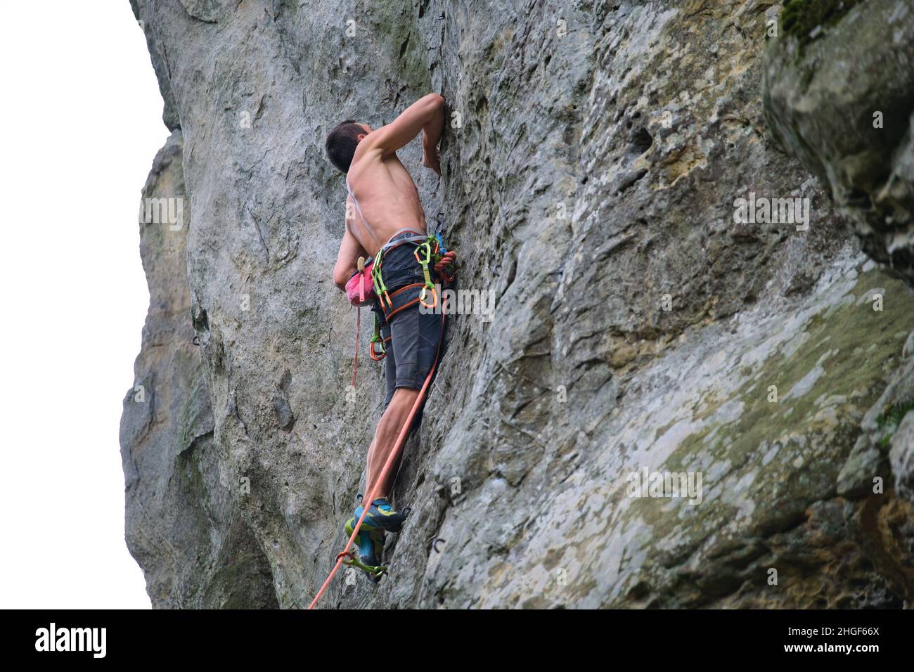 Young man climbing steep wall of rocky mountain. Male climber overcomes ...