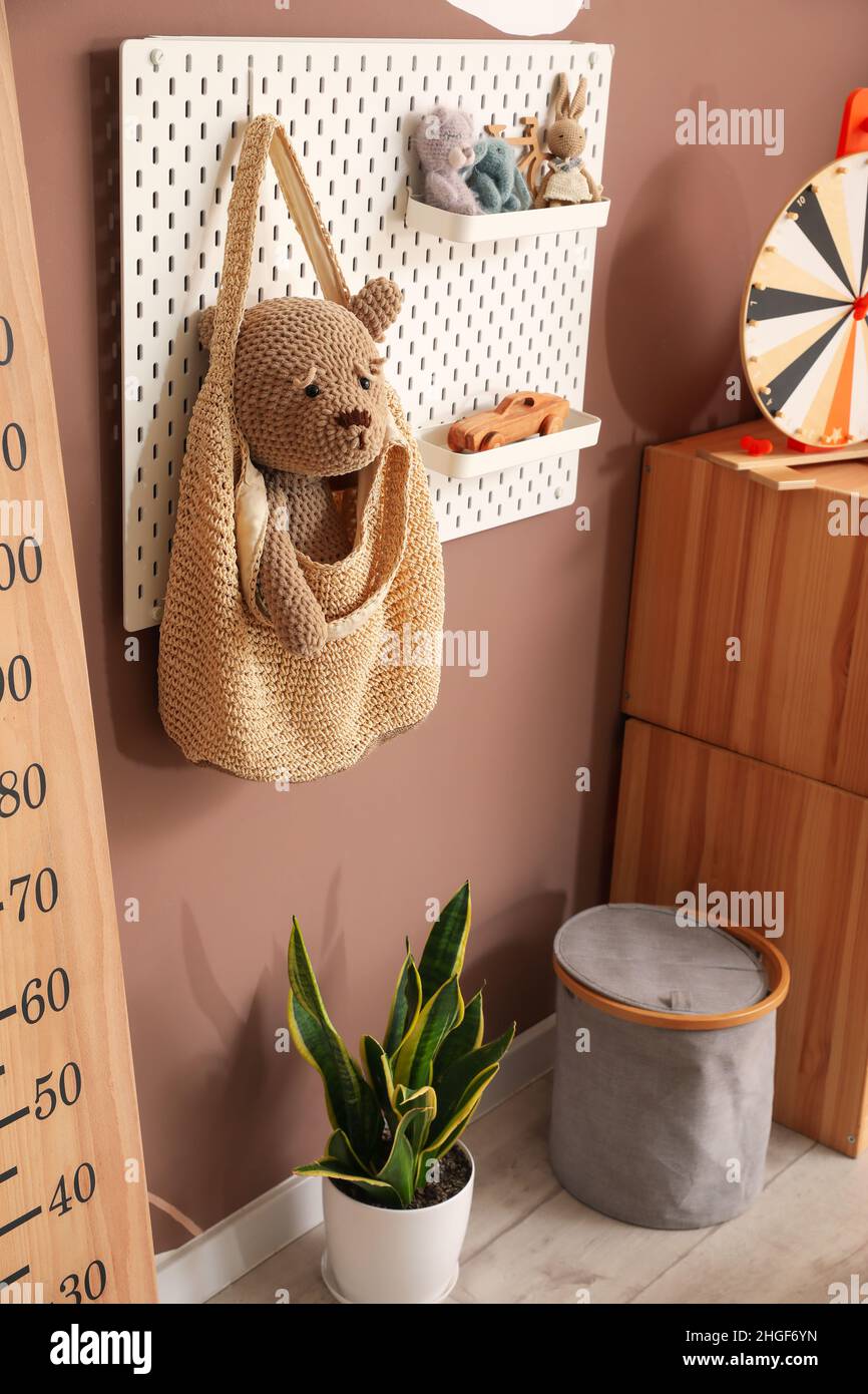 Pegboard with bag and toys hanging on color wall in children's playroom ...