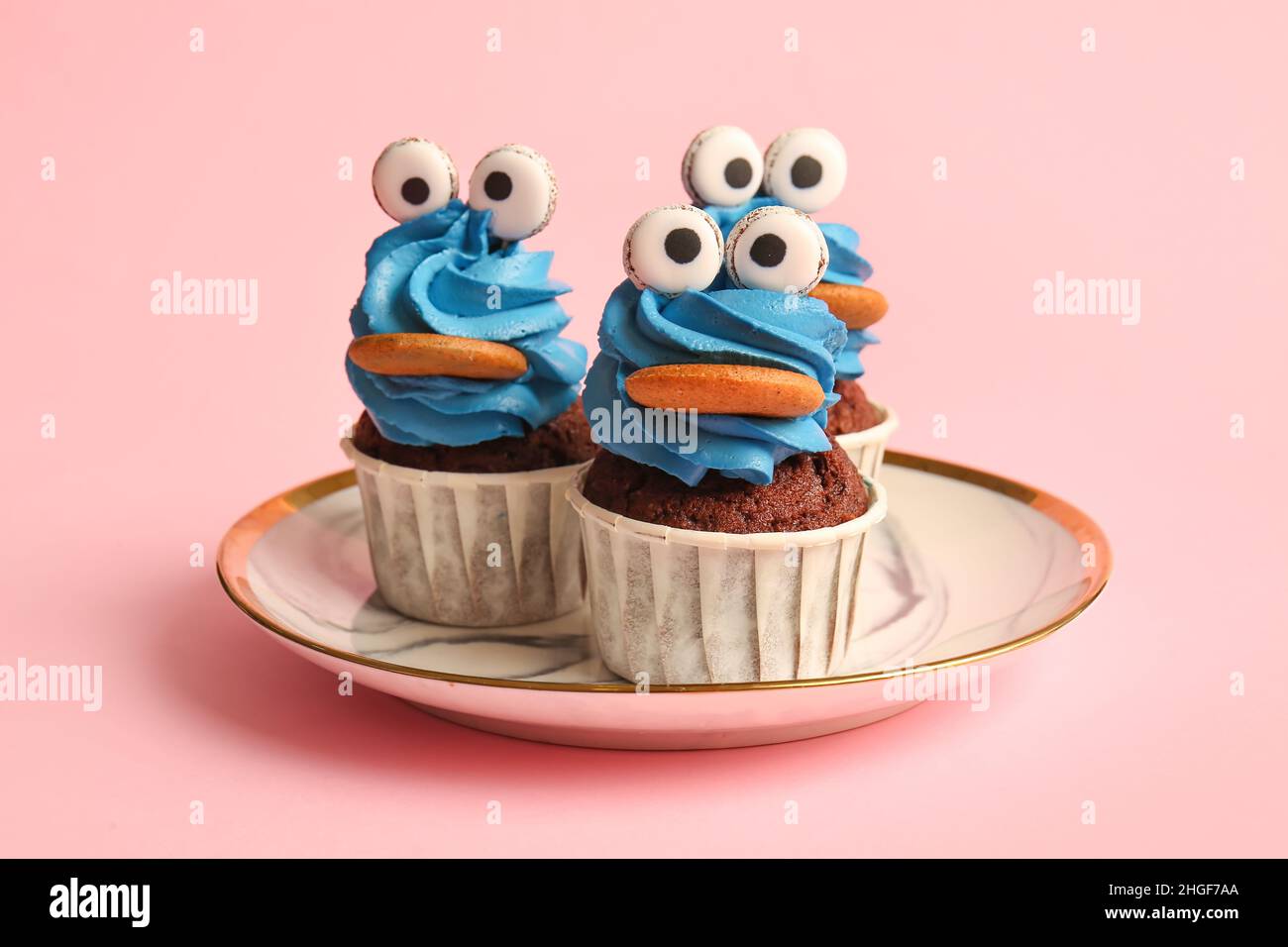 Plate with tasty funny cupcakes for Halloween celebration on pink ...