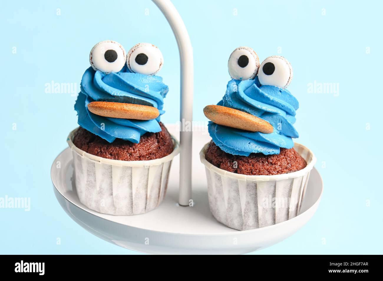 Stand with tasty funny cupcakes for Halloween celebration on blue ...
