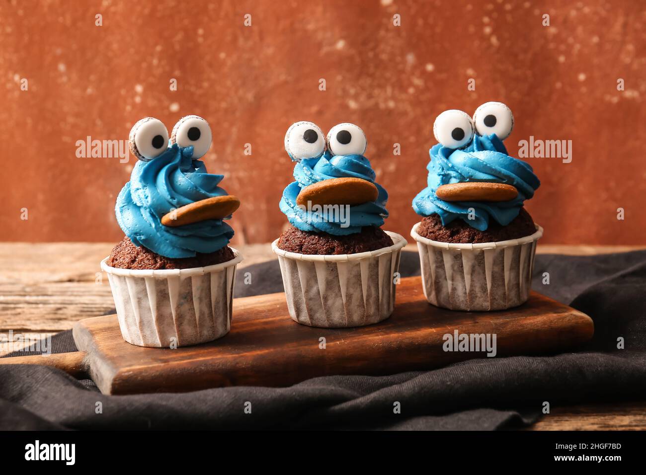 Board with tasty funny cupcakes for Halloween celebration on table ...