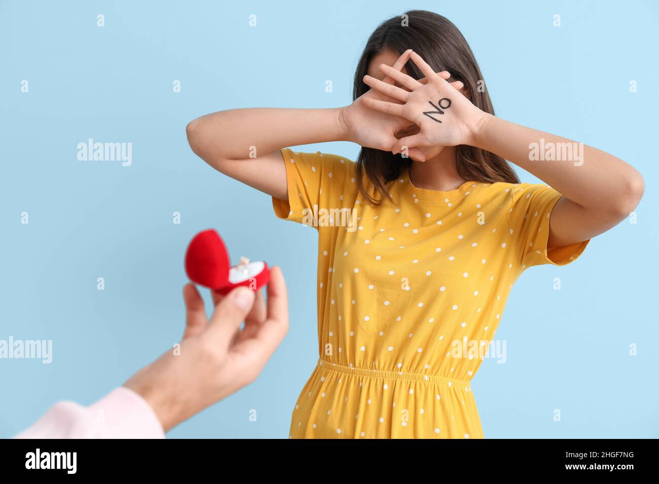 Young woman rejecting marriage proposal on blue background Stock Photo ...
