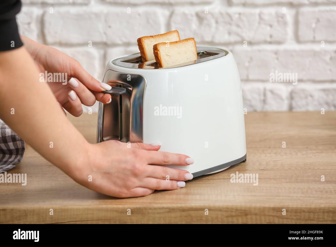 Woman making toasts near white brick wall Stock Photo - Alamy
