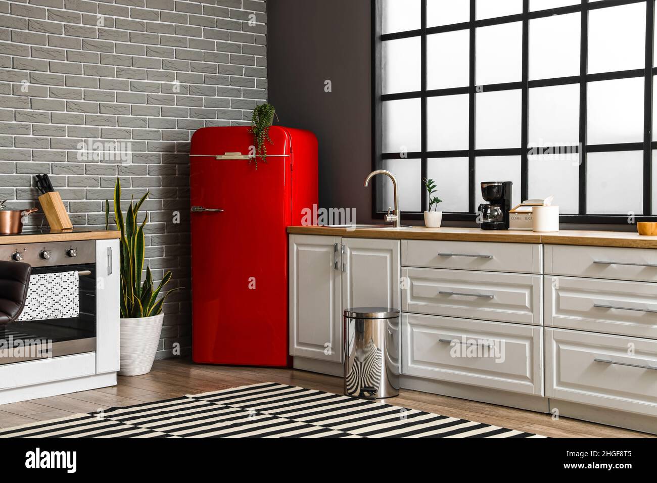Interior of stylish kitchen with red fridge, white counters and window ...