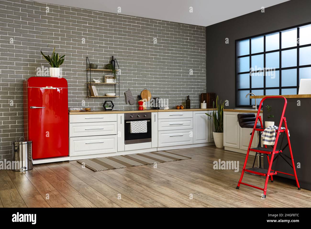 Interior of stylish kitchen with red fridge, white counters and window ...