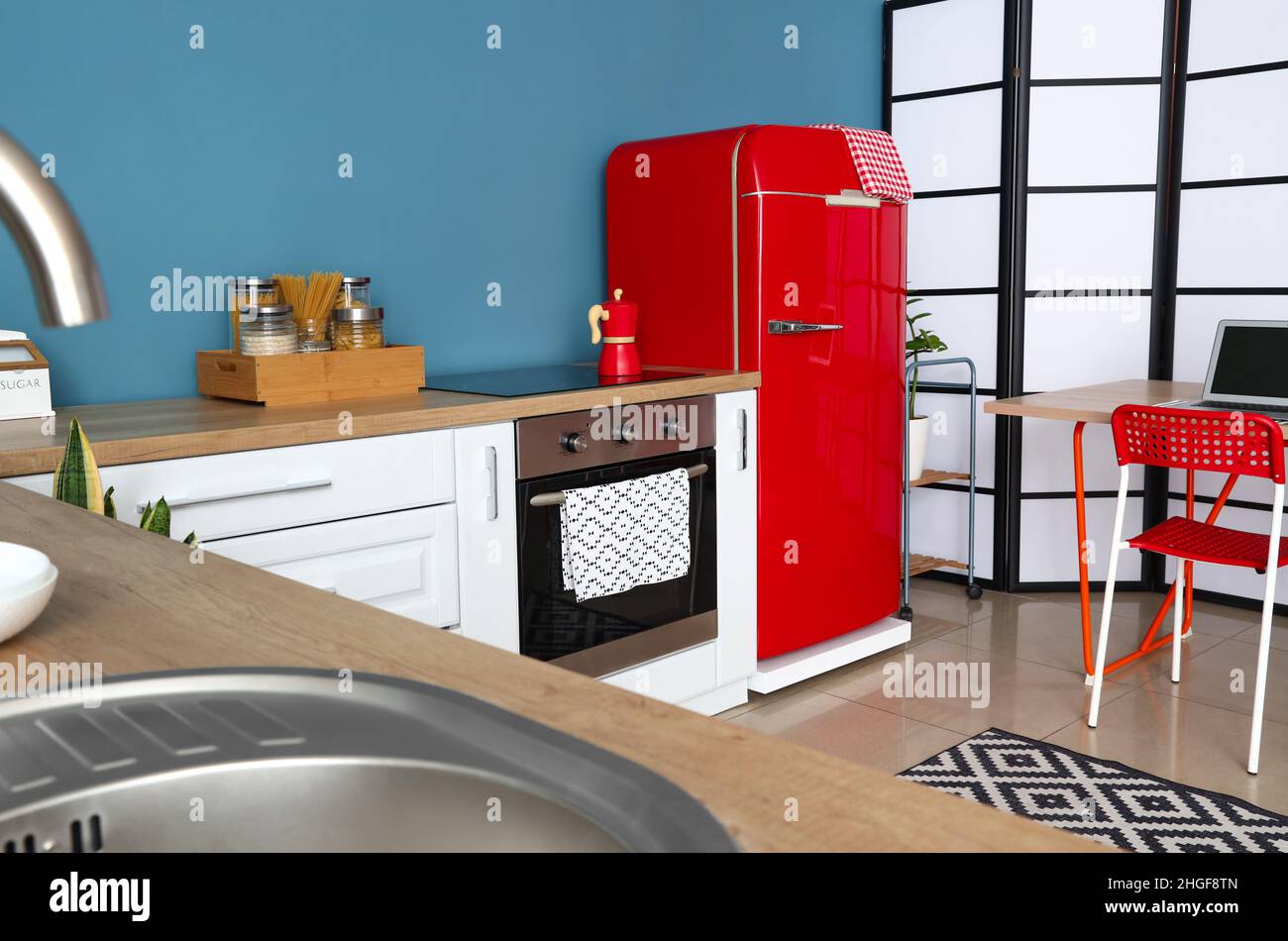 Interior of stylish kitchen with red fridge, white counters and blue ...