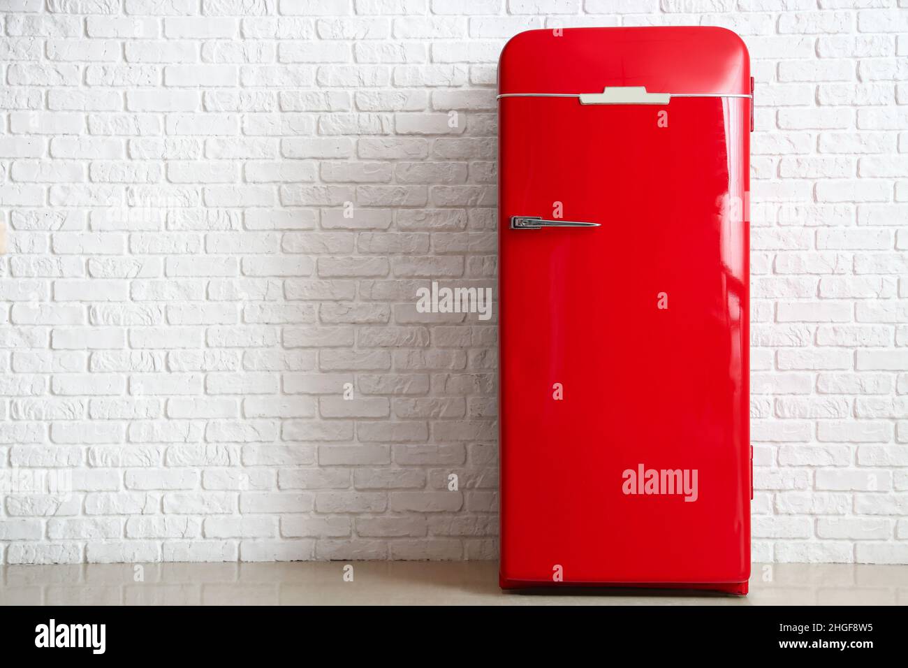 Red fridge near white brick wall Stock Photo - Alamy