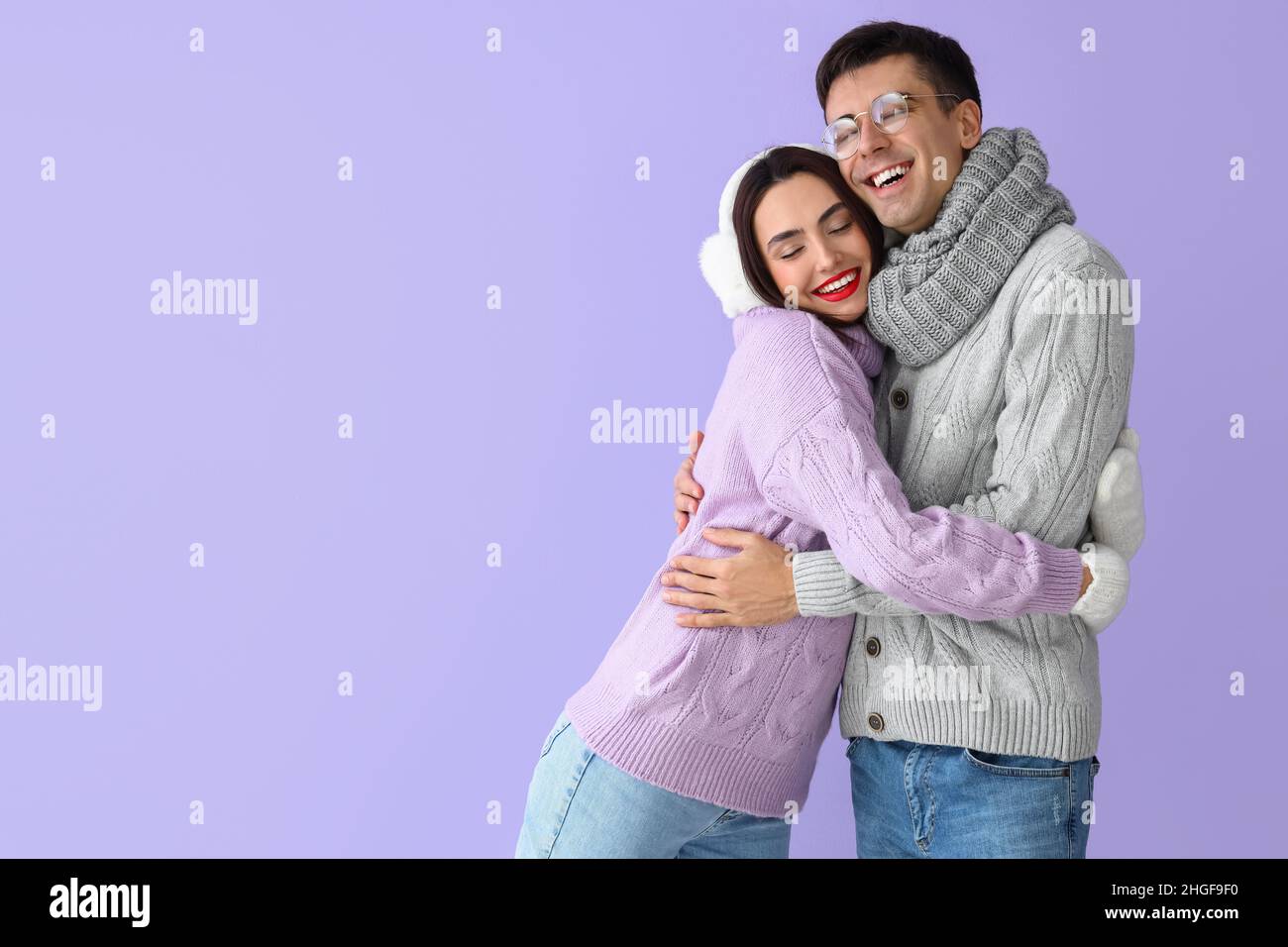 Hugging young couple in warm sweaters on color background Stock Photo ...