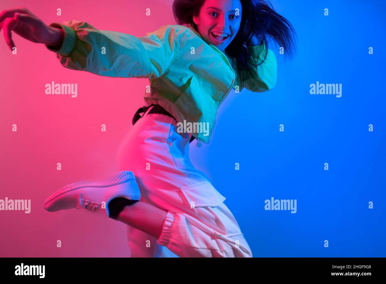 The brunette dances in neon, the dancer in red-blue. Hip hop girl ...