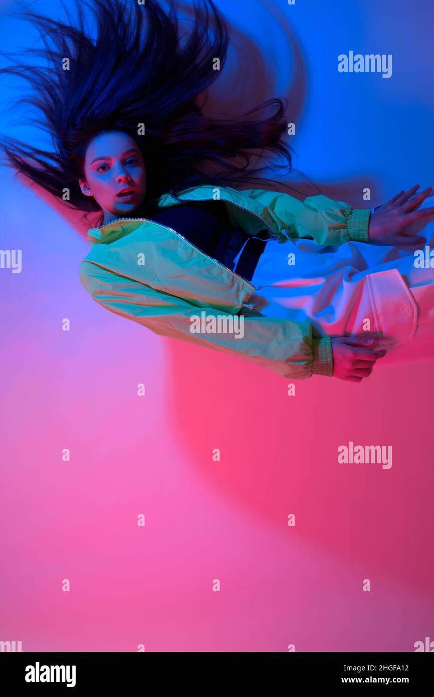 The brunette dances in neon, the dancer in red-blue. Hip hop girl ...